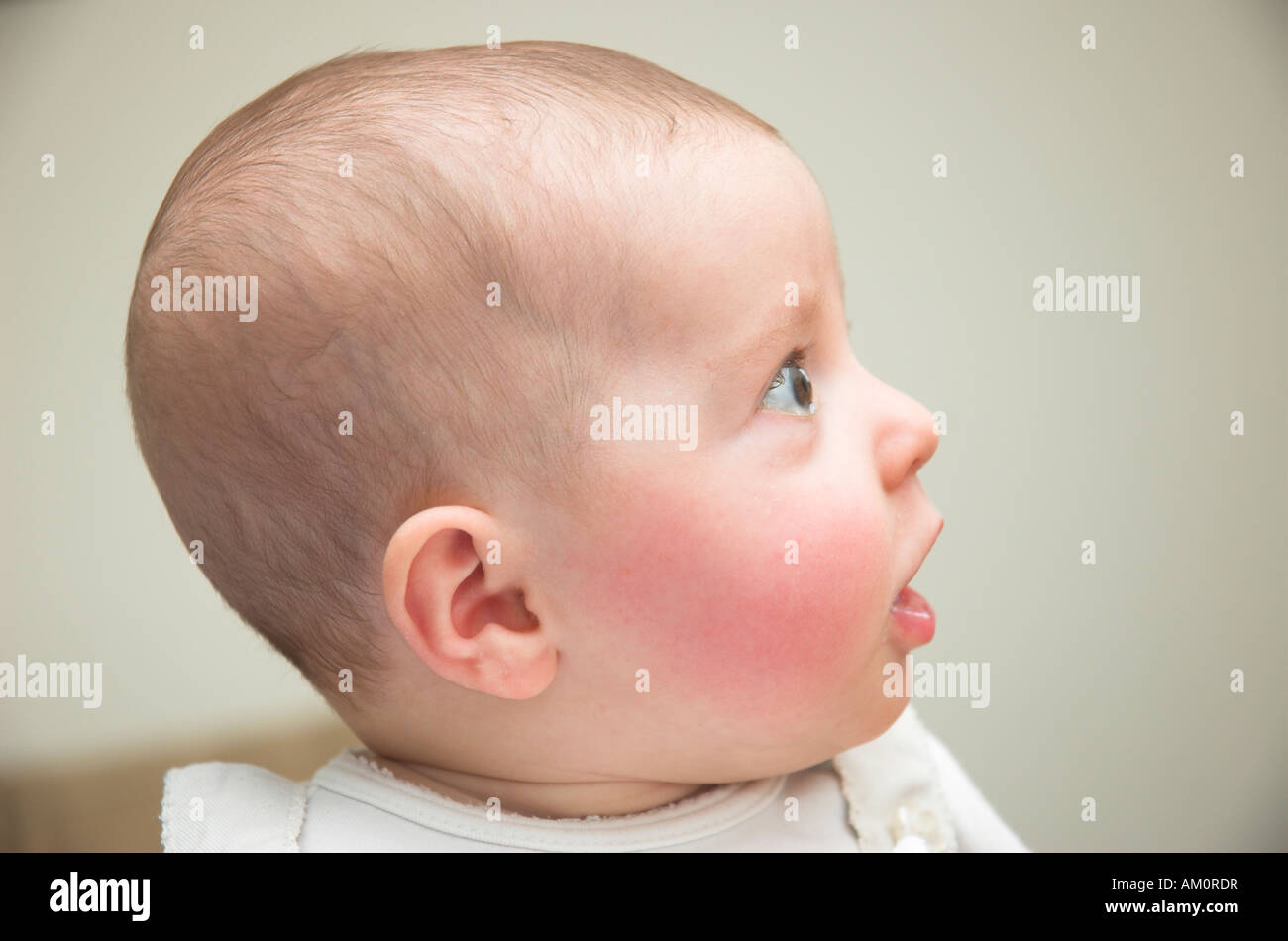 A baby looking to her side with a beautiful expression of wonder and ...