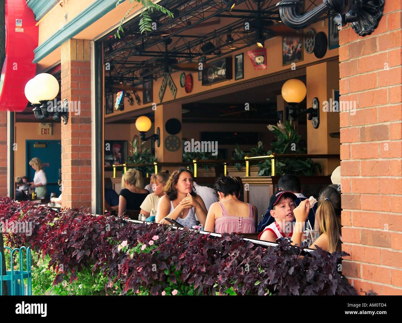 Tourists enjoying a meal at a sidewalk restaurant near Niagara Falls, Canada, with a bustling ...