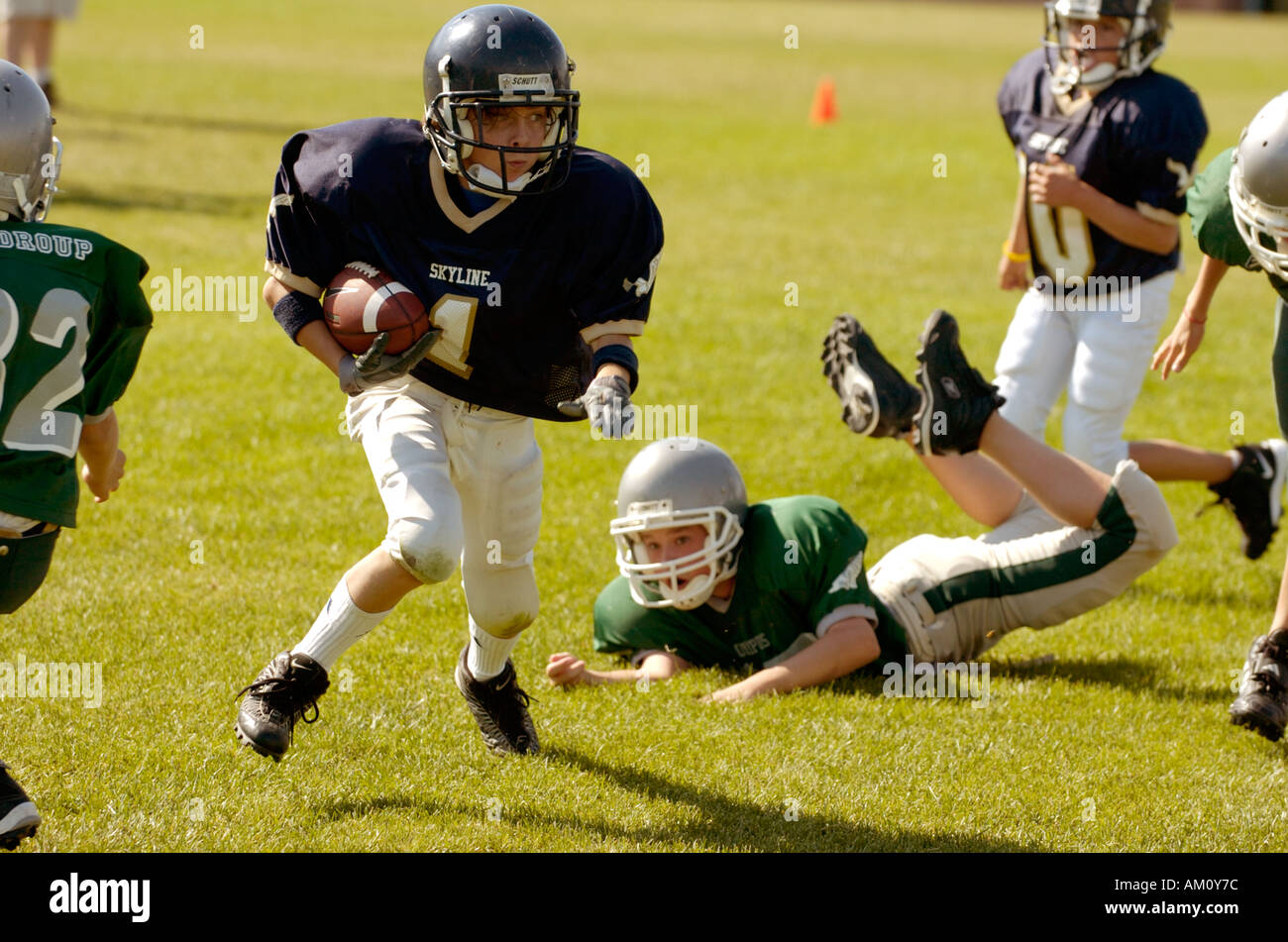 Football player running past fallen defender Stock Photo - Alamy