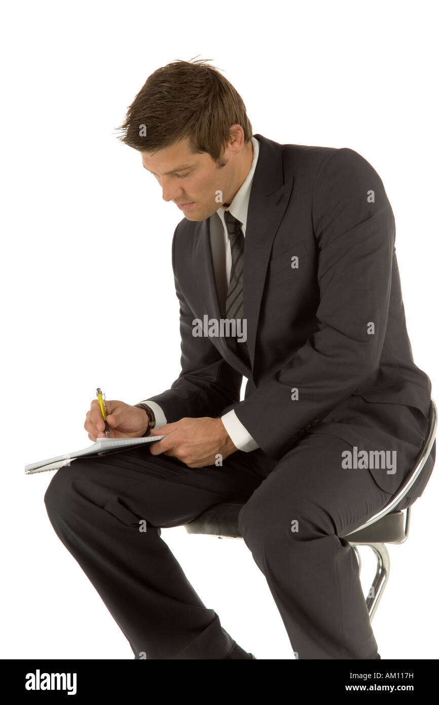 Young man in an office setting taking notes against a white background ...