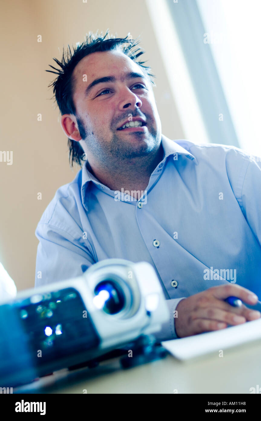 an unshaved man watching a video projector presentation is an office ...