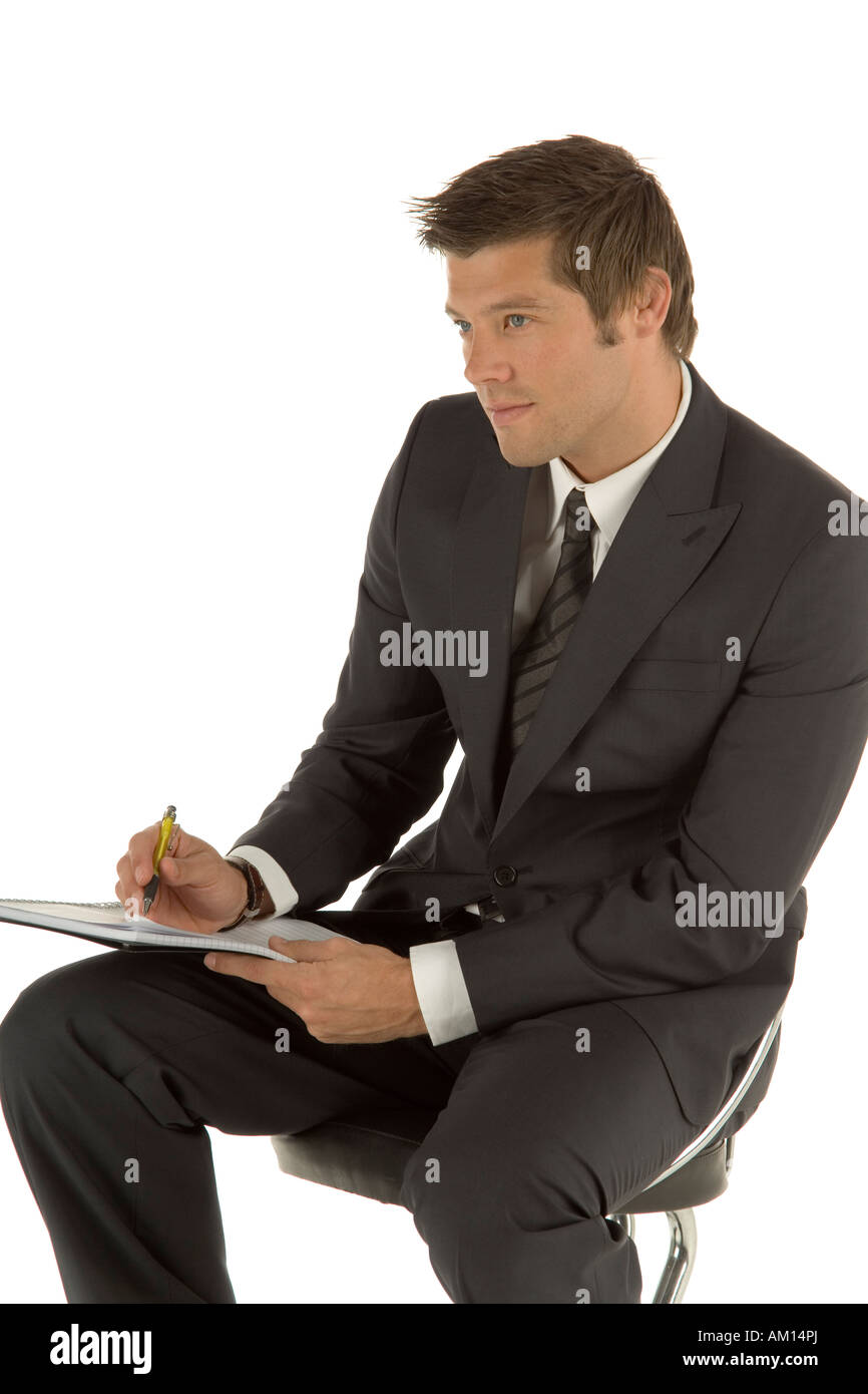 Young man in an office setting taking notes against a white background ...