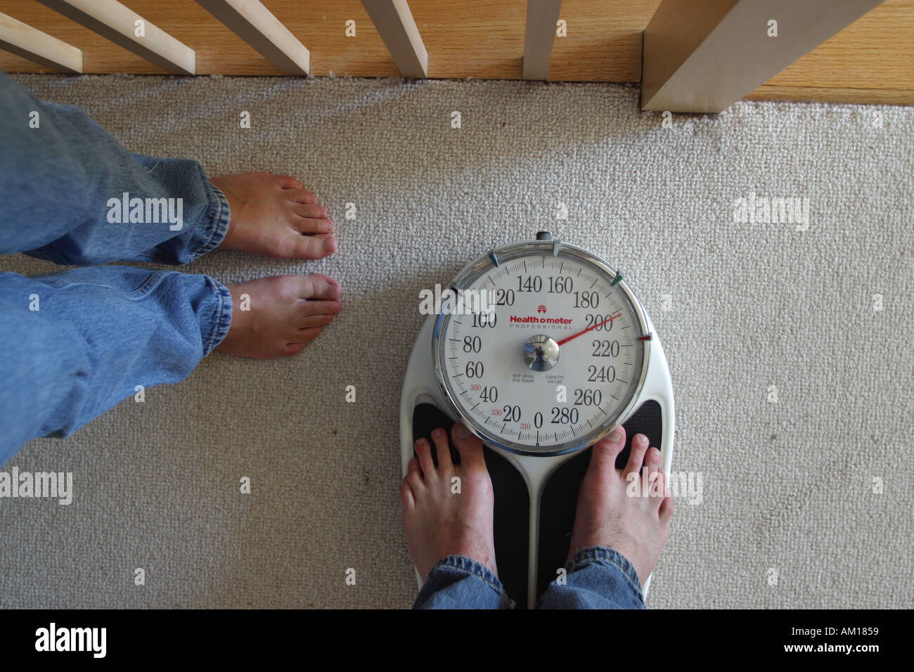 Man on Scale with Wife watching Wife Stock Photo - Alamy