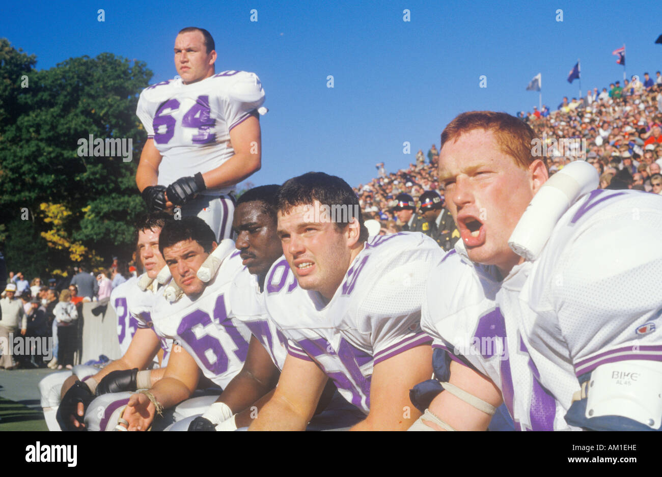 Group of College football players observing game from the bench West ...
