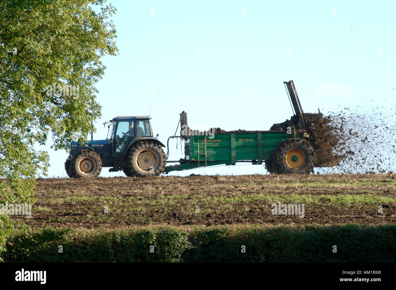 Tractor and trailer spreading muck on set aside field before reseeding ...