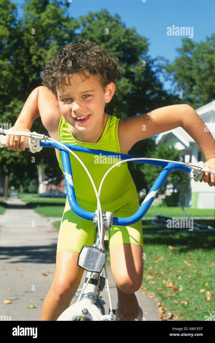 Portrait of girl on sidewalk leaning forward over bicycle handle bars ...