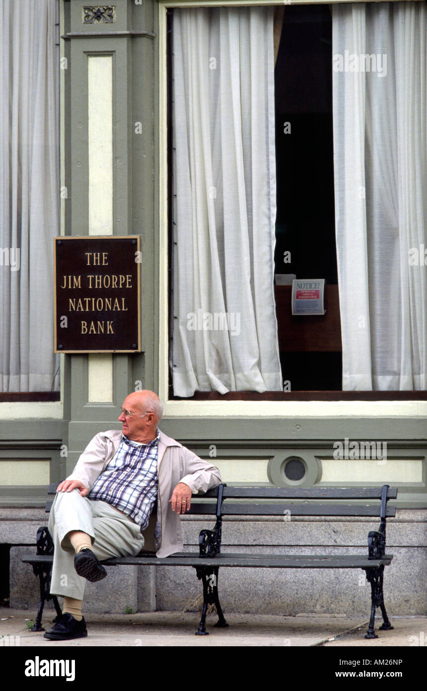A man sits on a bench outside a bank in Jim Thorpe Pennsylvania Stock ...