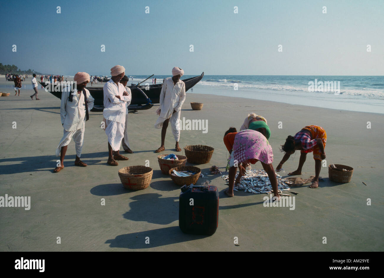 INDIA Goa Colva Beach Three men in turbans watching three women sorting ...