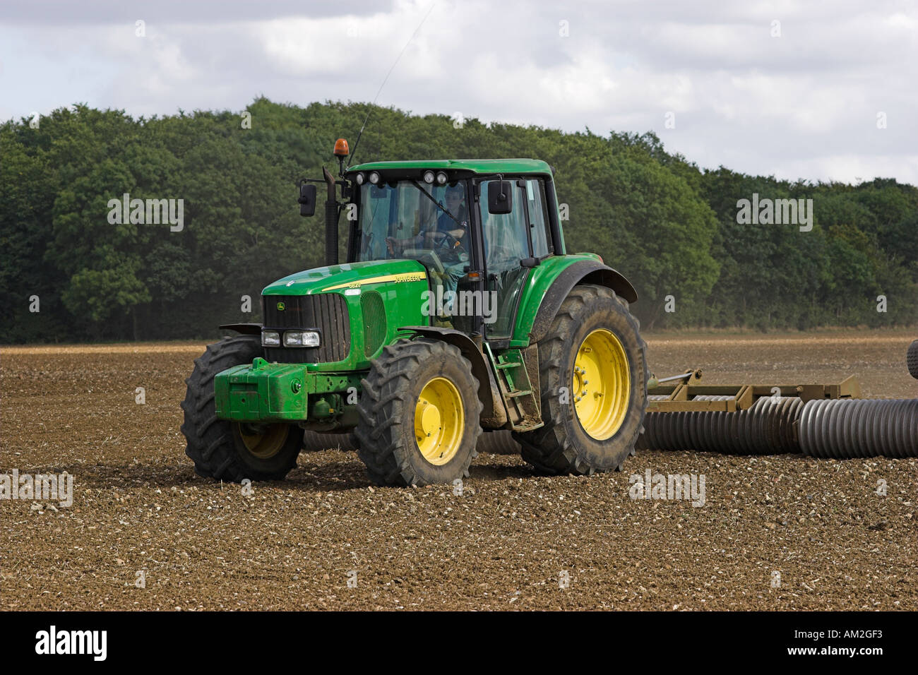 Tractor rolling a recently ploughed field Stock Photo - Alamy
