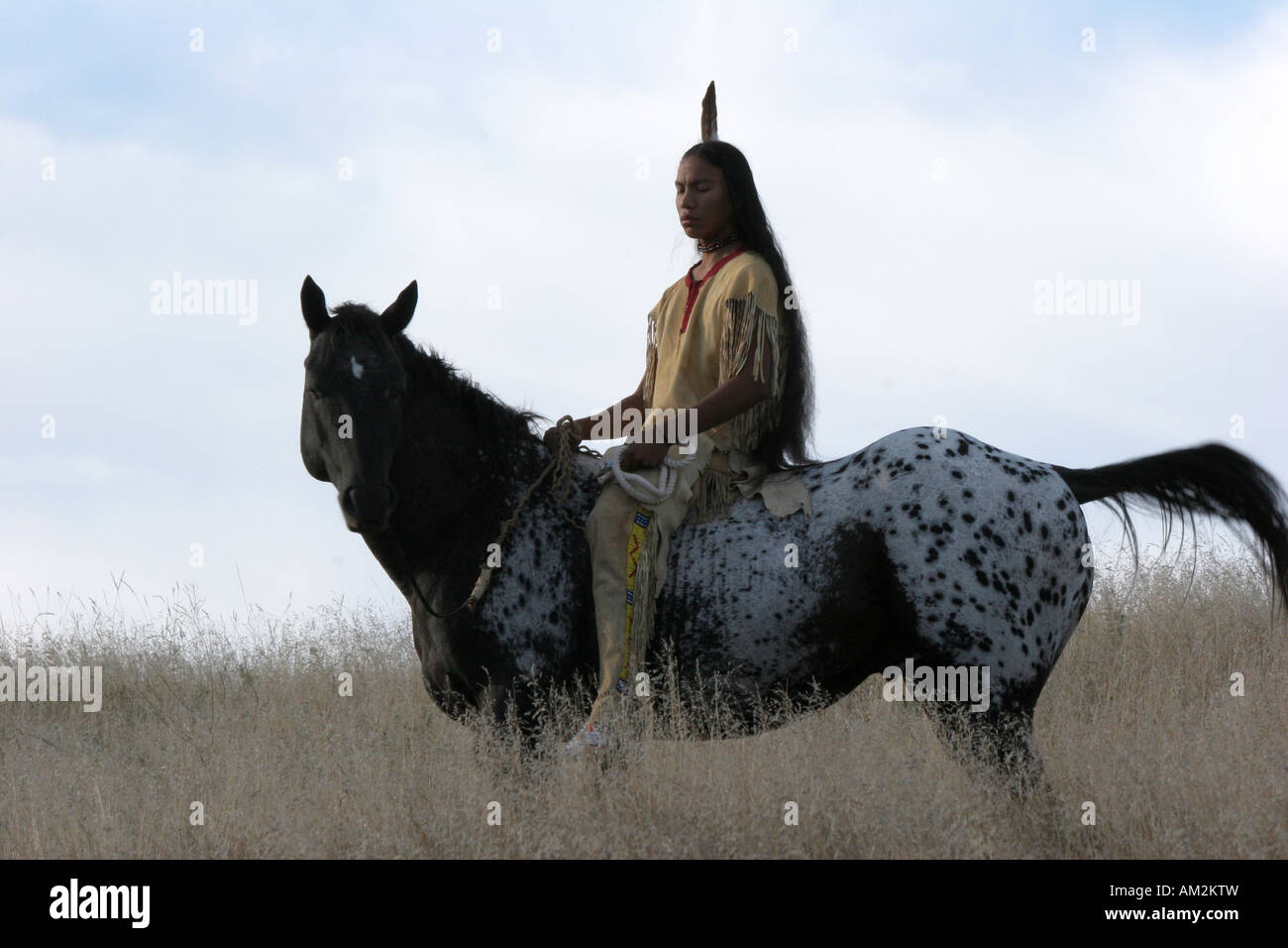 A Native American Indian man sitting bareback on a horse in traditional ...