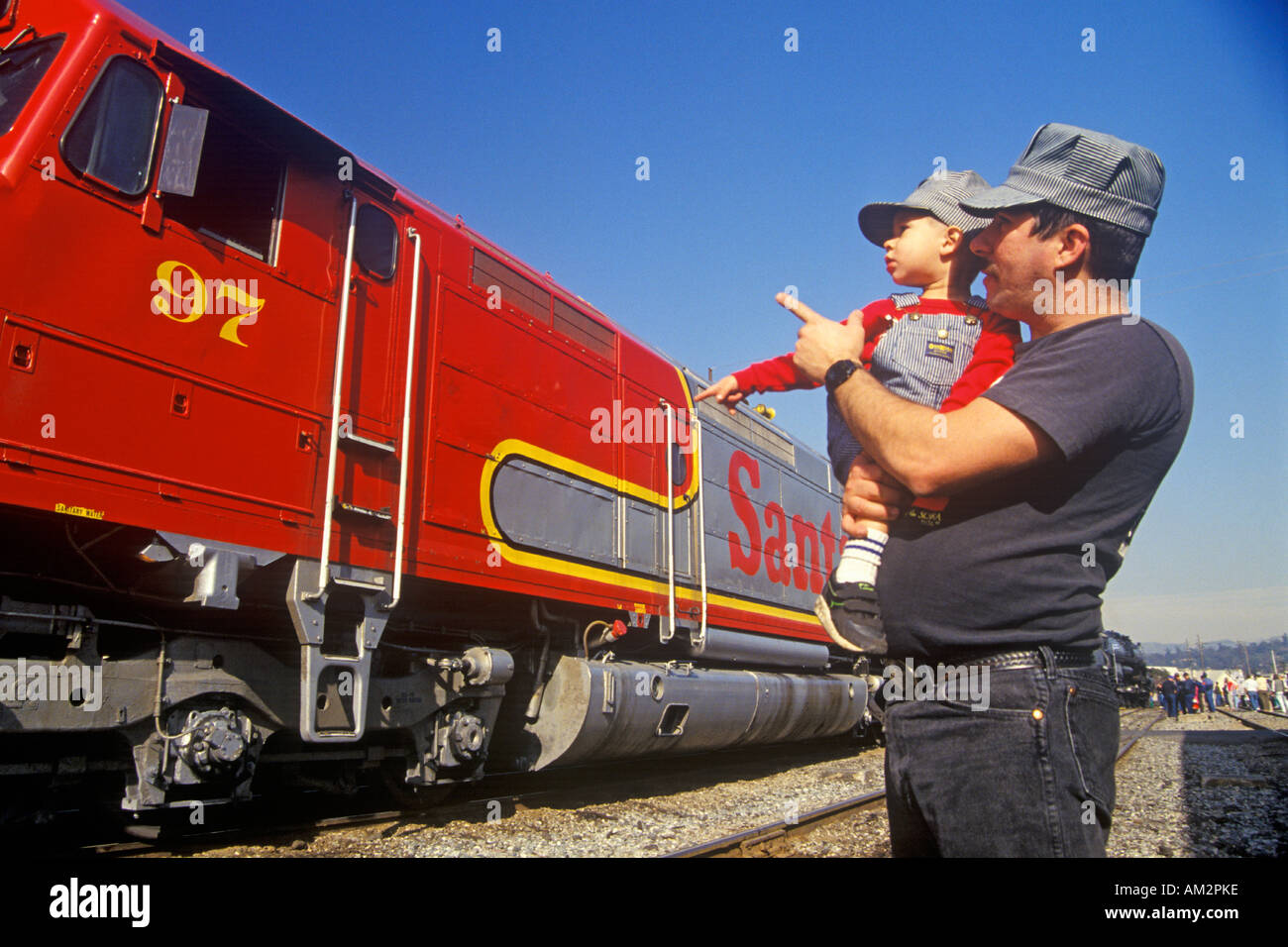 A father and son in engineer caps look at a historic Santa Fe diesel ...