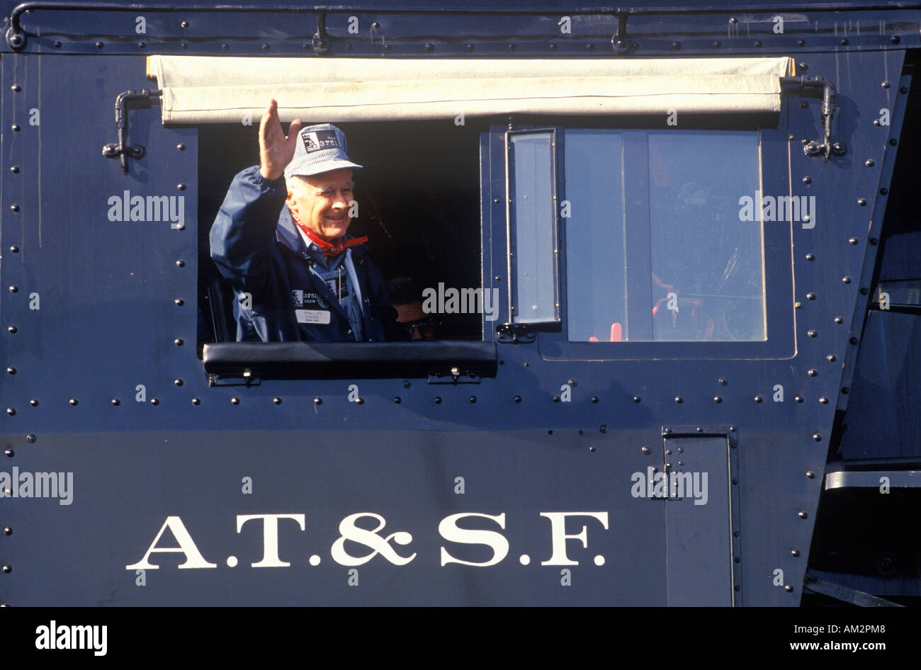 A locomotive engineer waves from the window of an engine of the ...