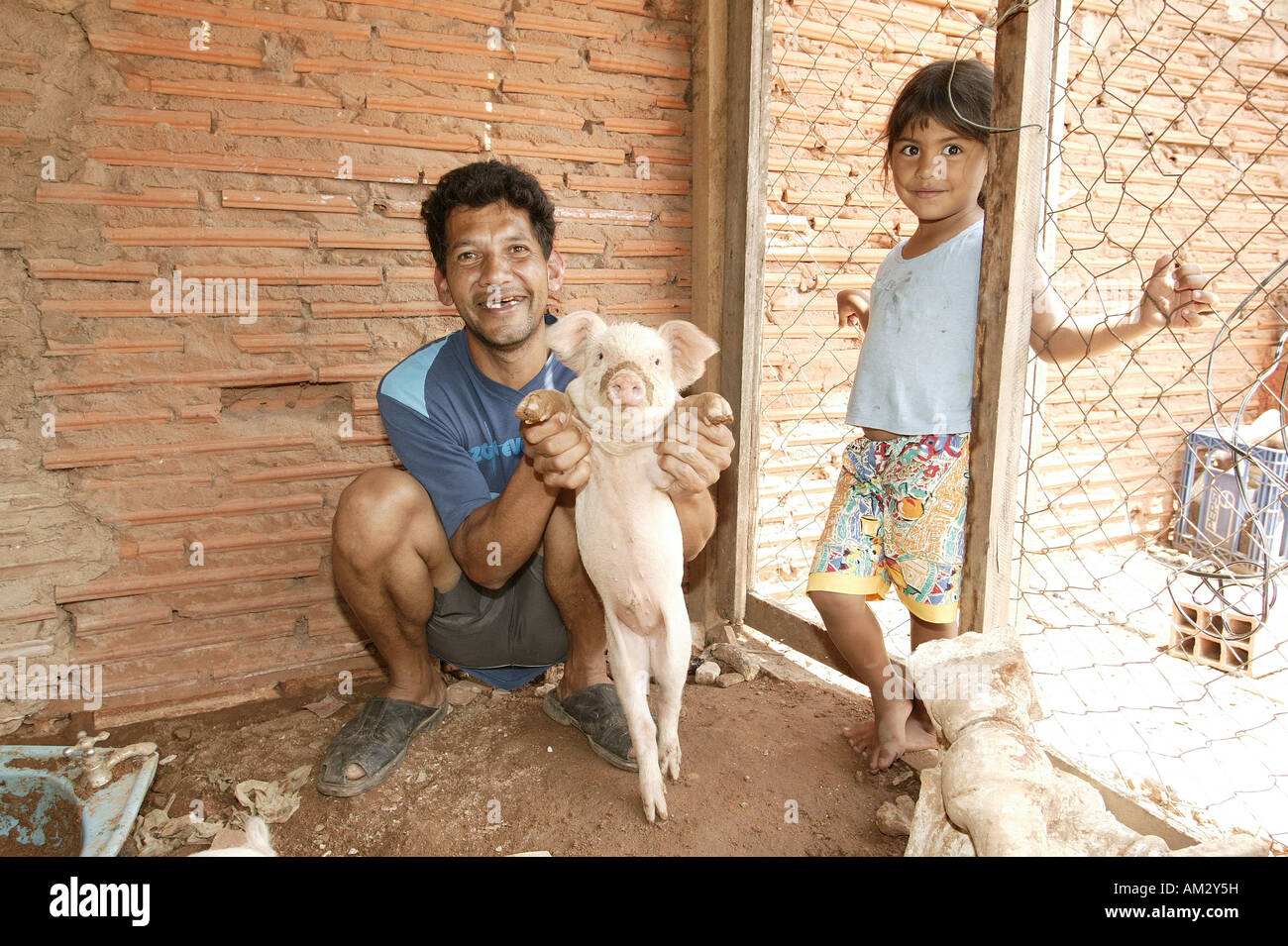 Guarani father and daughter with piglets, in the poor area of Chacarita ...