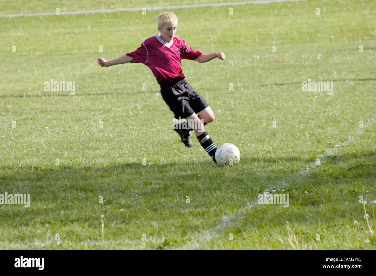 Teenage soccer player kicking the football down the field on an ...