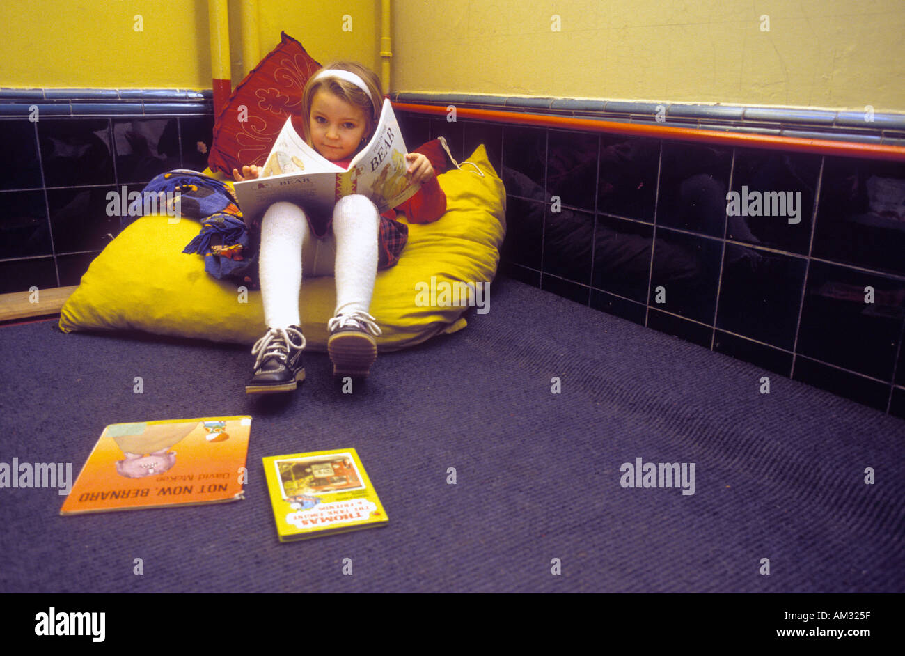Girl reading book on big pillow in corner of classroom Stock Photo - Alamy
