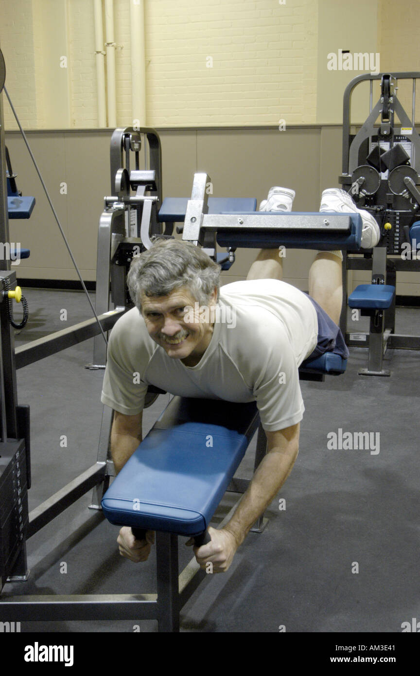 Older man exercising with leg curl machine Stock Photo - Alamy
