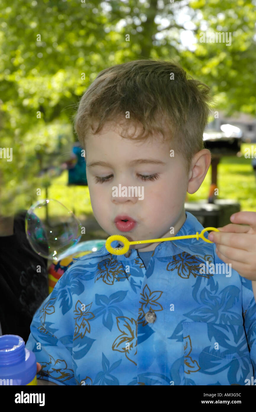 Young 3 year old boy blowing soap bubbles outside Stock Photo - Alamy