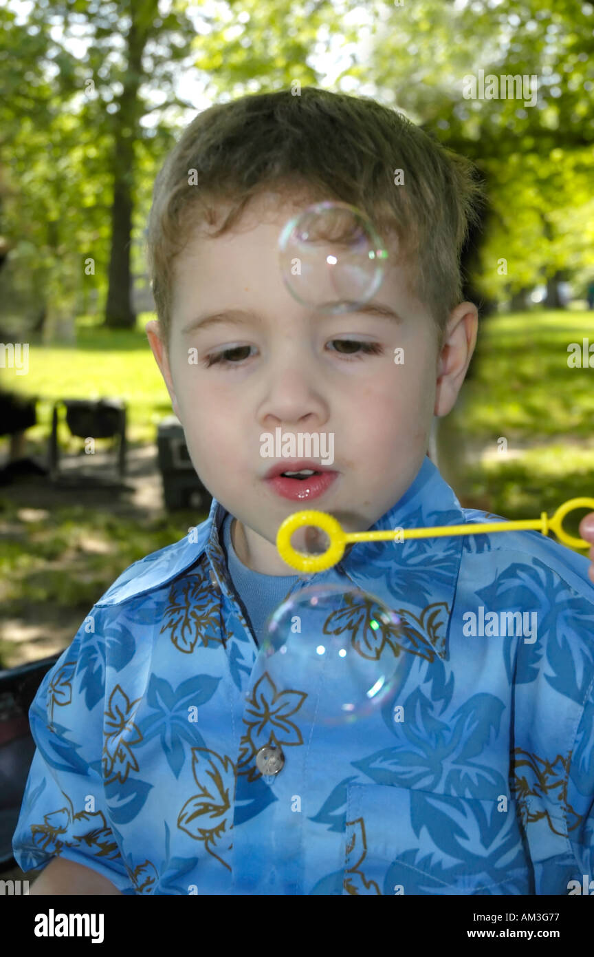 Young 3 year old boy blowing soap bubbles outside Stock Photo - Alamy