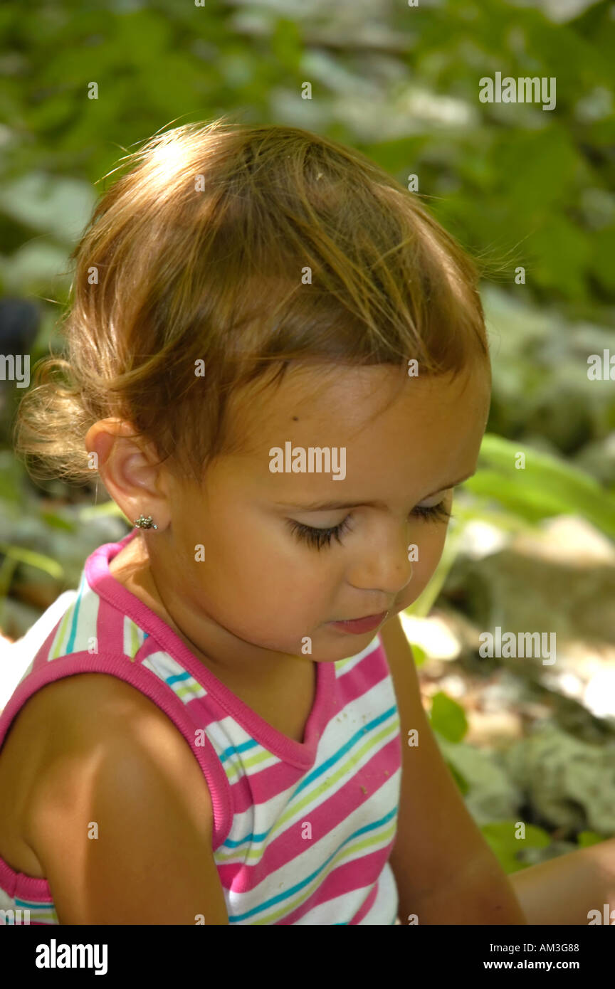 Portrait of young girl with her eyes cast down while playing in the ...