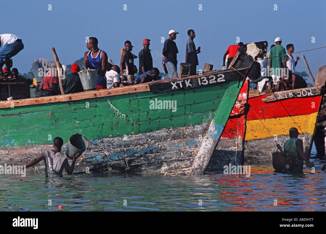 Boats moored beside the fish market passing fish from boat to bucket to ...
