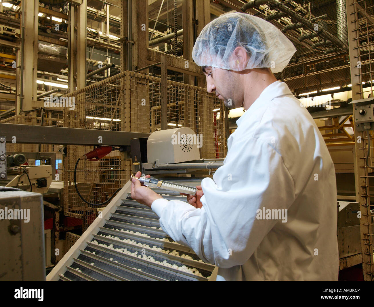 Man checking the size of Mentos during production of the candy in the ...