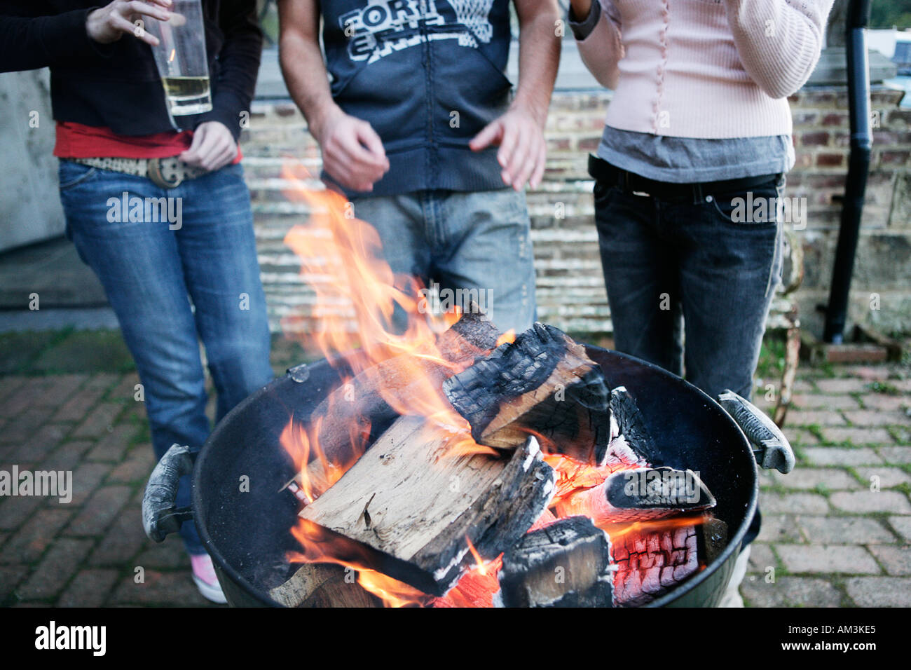 Friends standing around a fire Stock Photo - Alamy