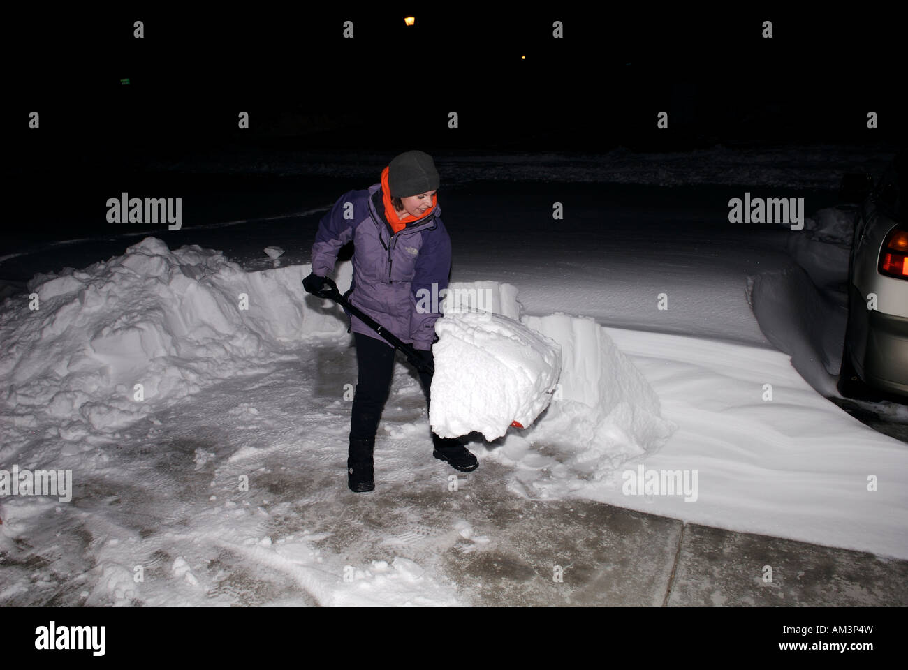 Young woman shovels a deep snow drift from her driveway during the ...
