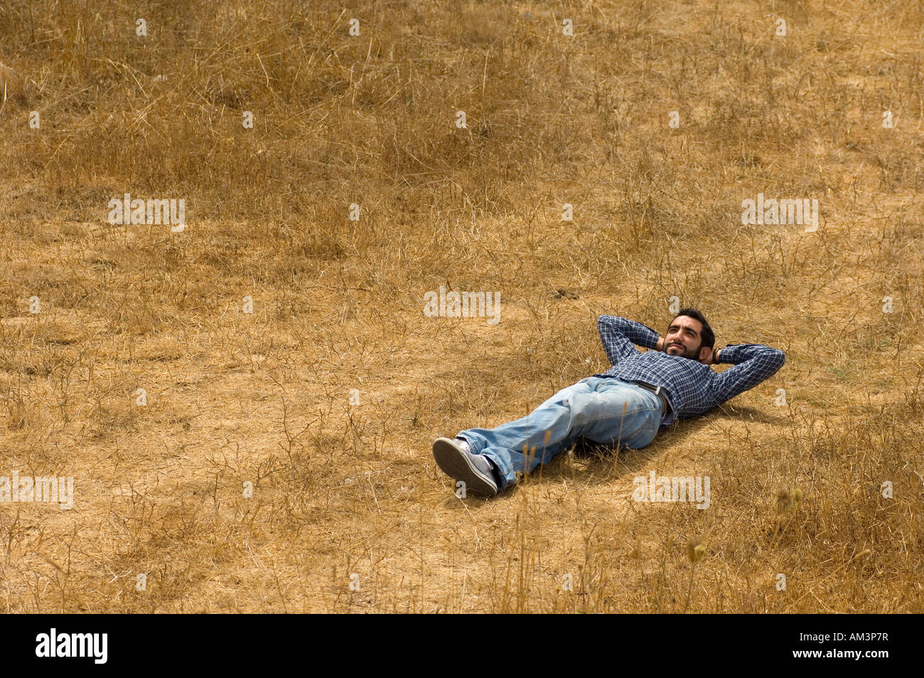 Young Arabic man laying in field alone Stock Photo - Alamy