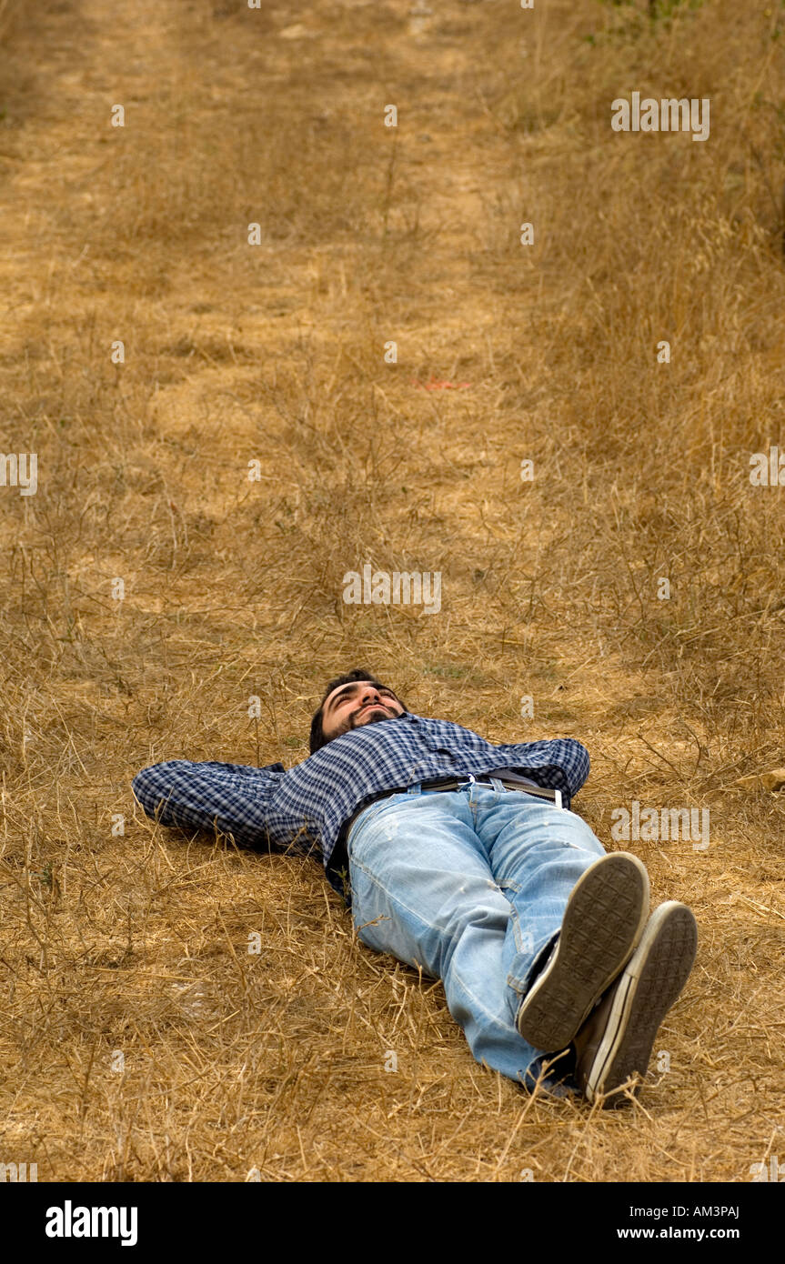 Young man laying in field alone Stock Photo - Alamy