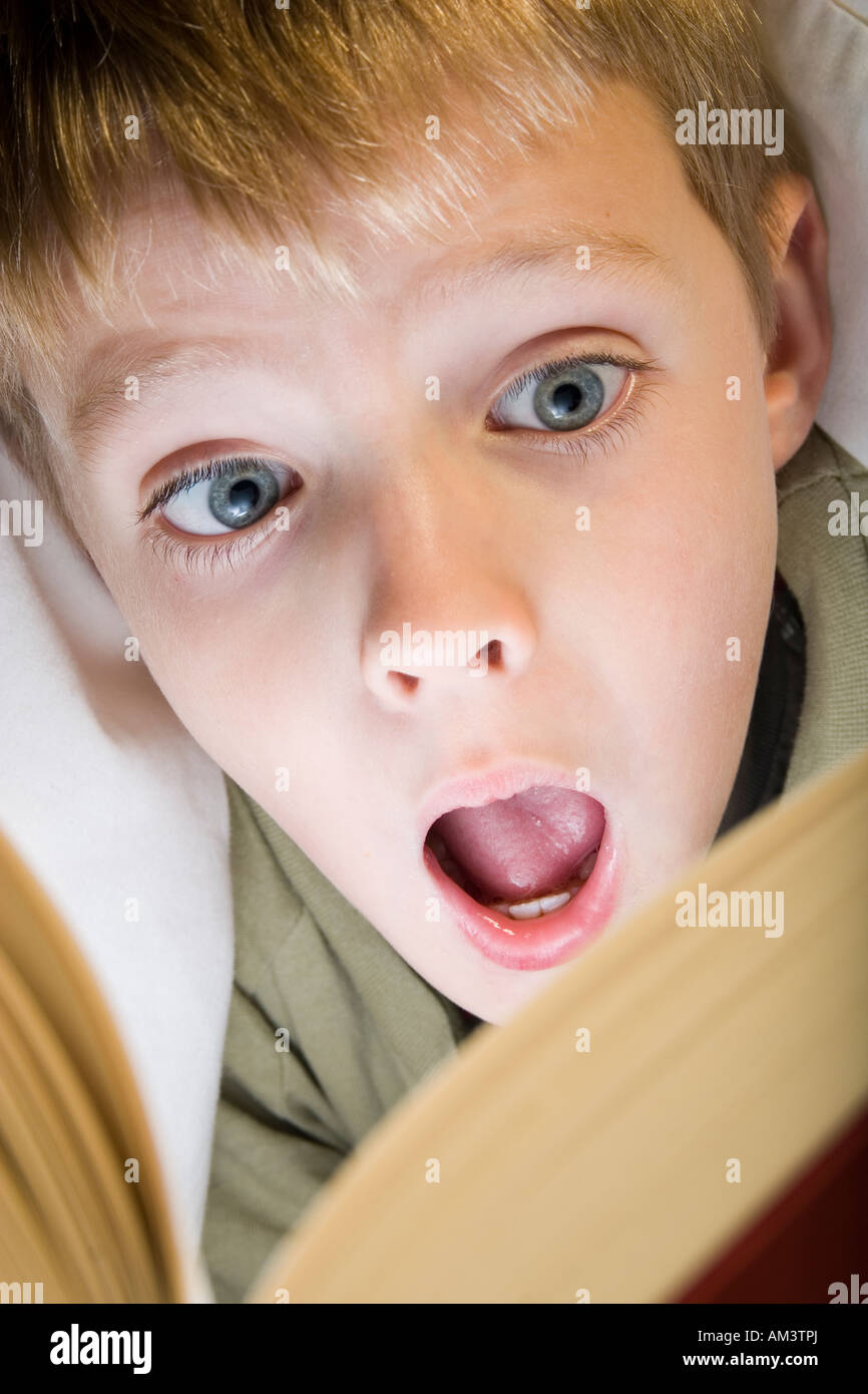 young boy looking amazed by book Stock Photo - Alamy
