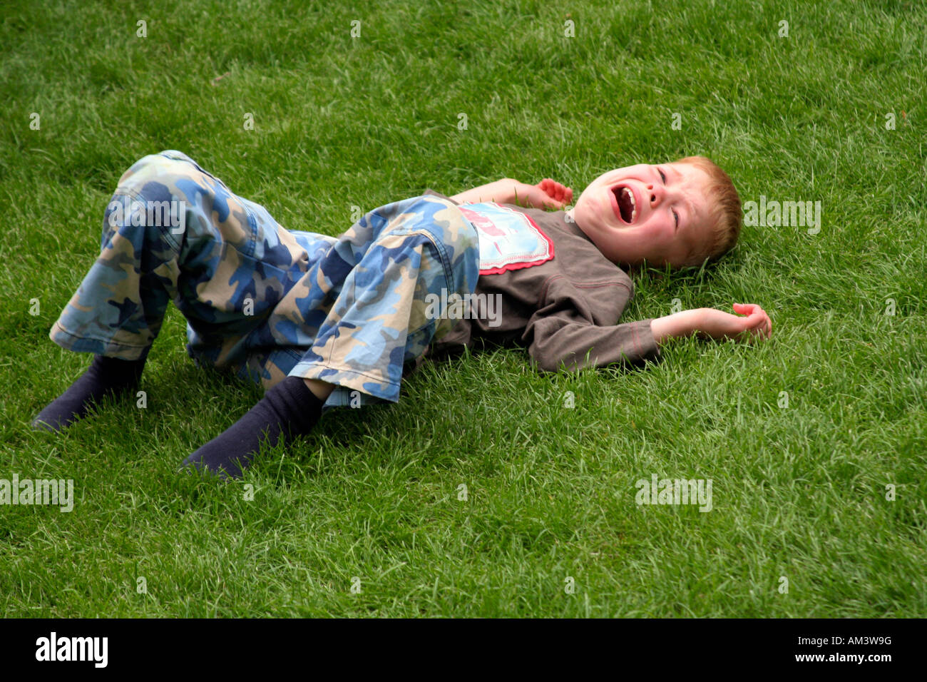 6 year old boy laying on ground crying Stock Photo - Alamy