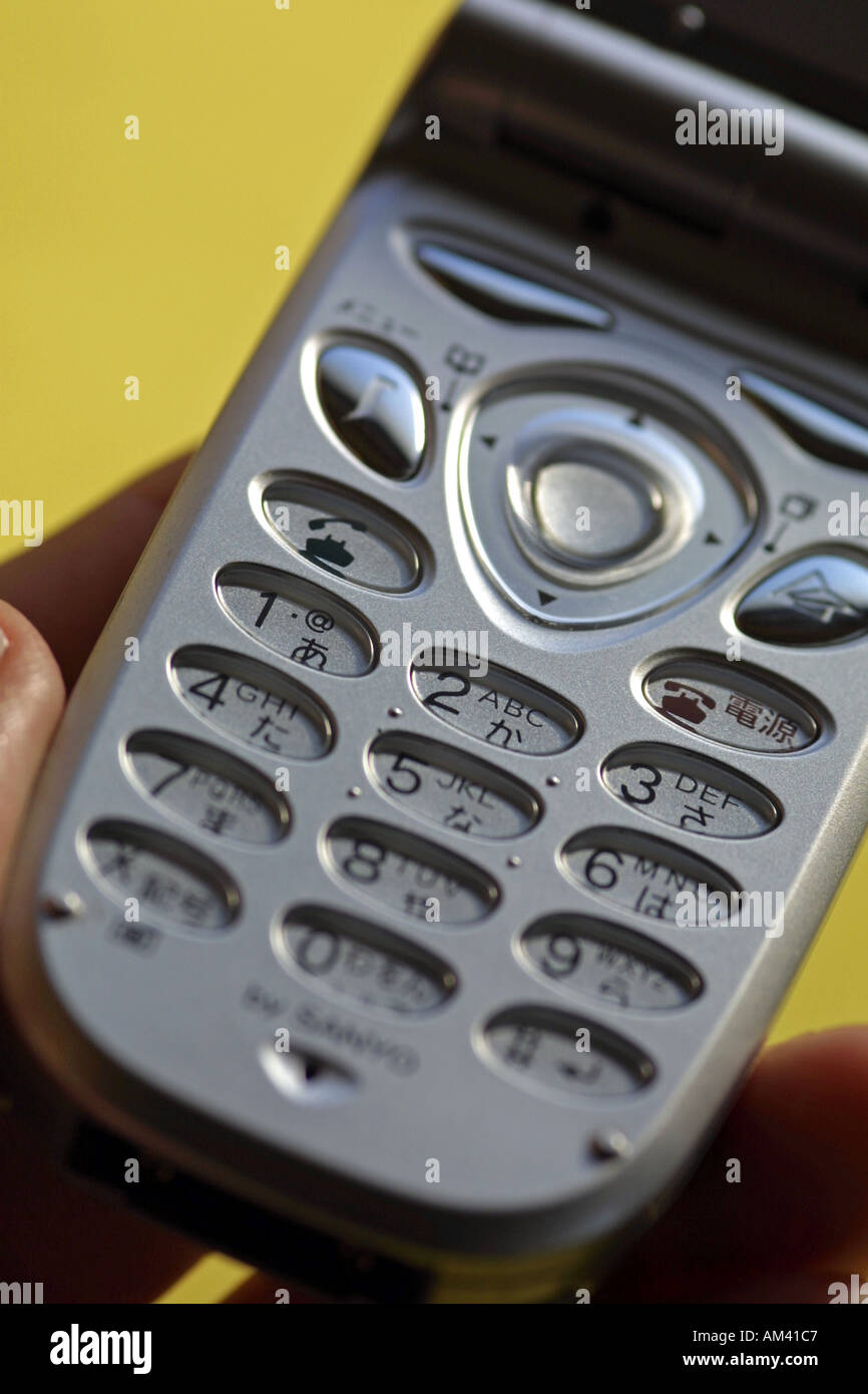 Mobile phone keypad flip type in a users hand close up yellow ...