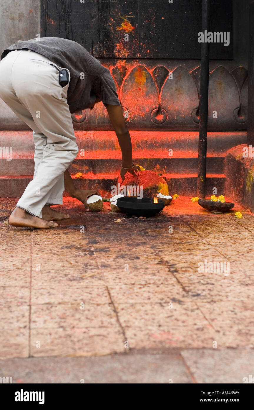 Rear view of a man applying sindoor on a rock, Tirupati, Tirumala ...