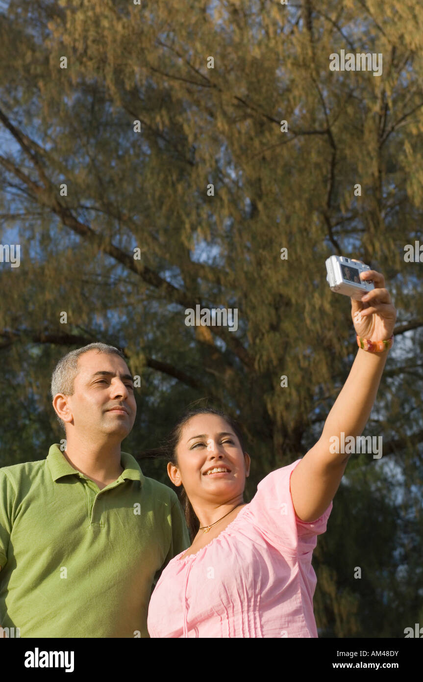 Low angle view of a mid adult couple taking a photograph of themselves ...