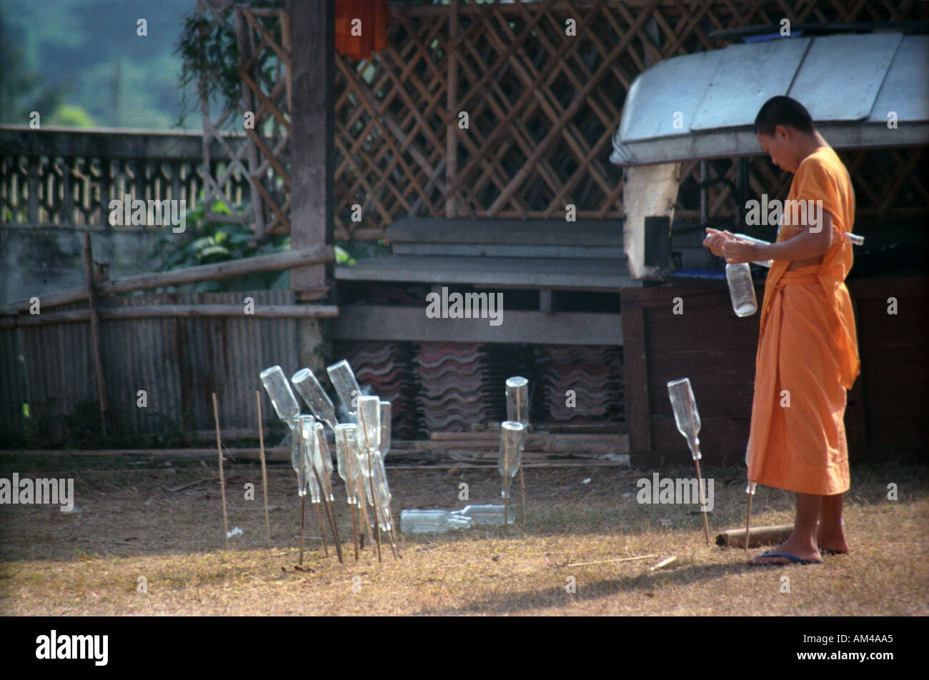 A Buddhist monk places empty bottles into sticks on the ground Stock ...
