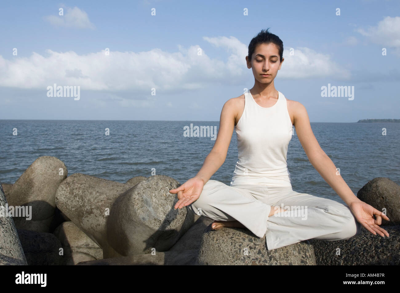 Young woman doing yoga on a rock Stock Photo - Alamy