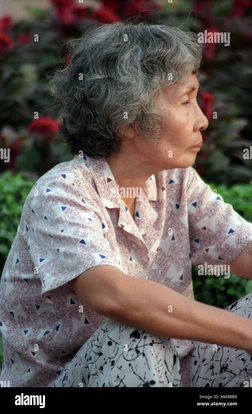 A Vietnamese woman wearing a typical hat sits under the shade in the ...