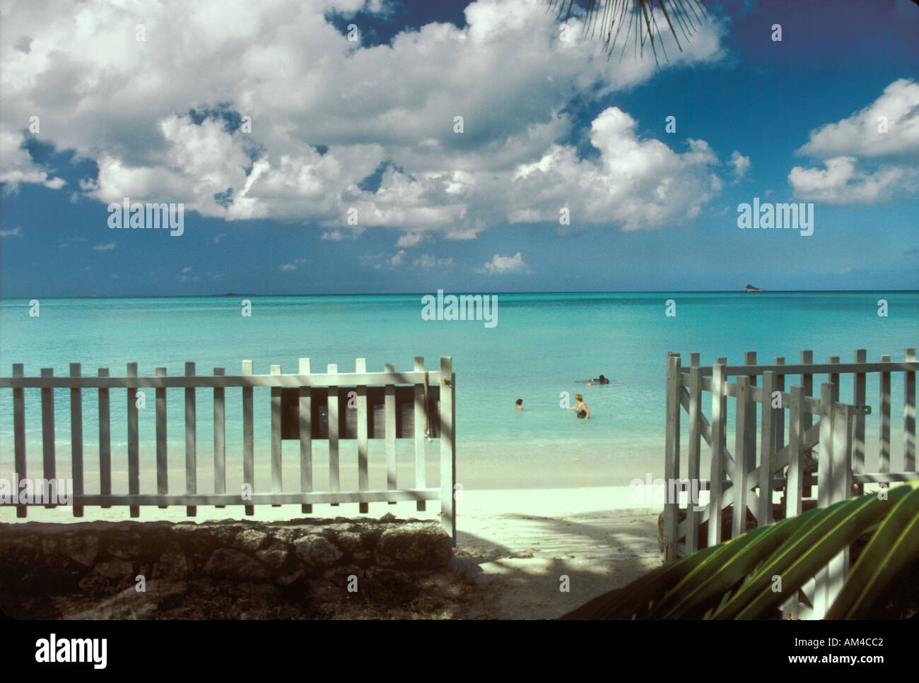Caribbean island beach with a picket fence and gate open to the sea ...
