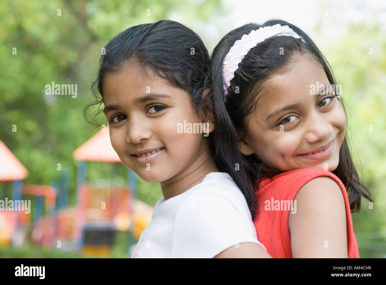 Portrait of two girls back to back and smiling Stock Photo - Alamy