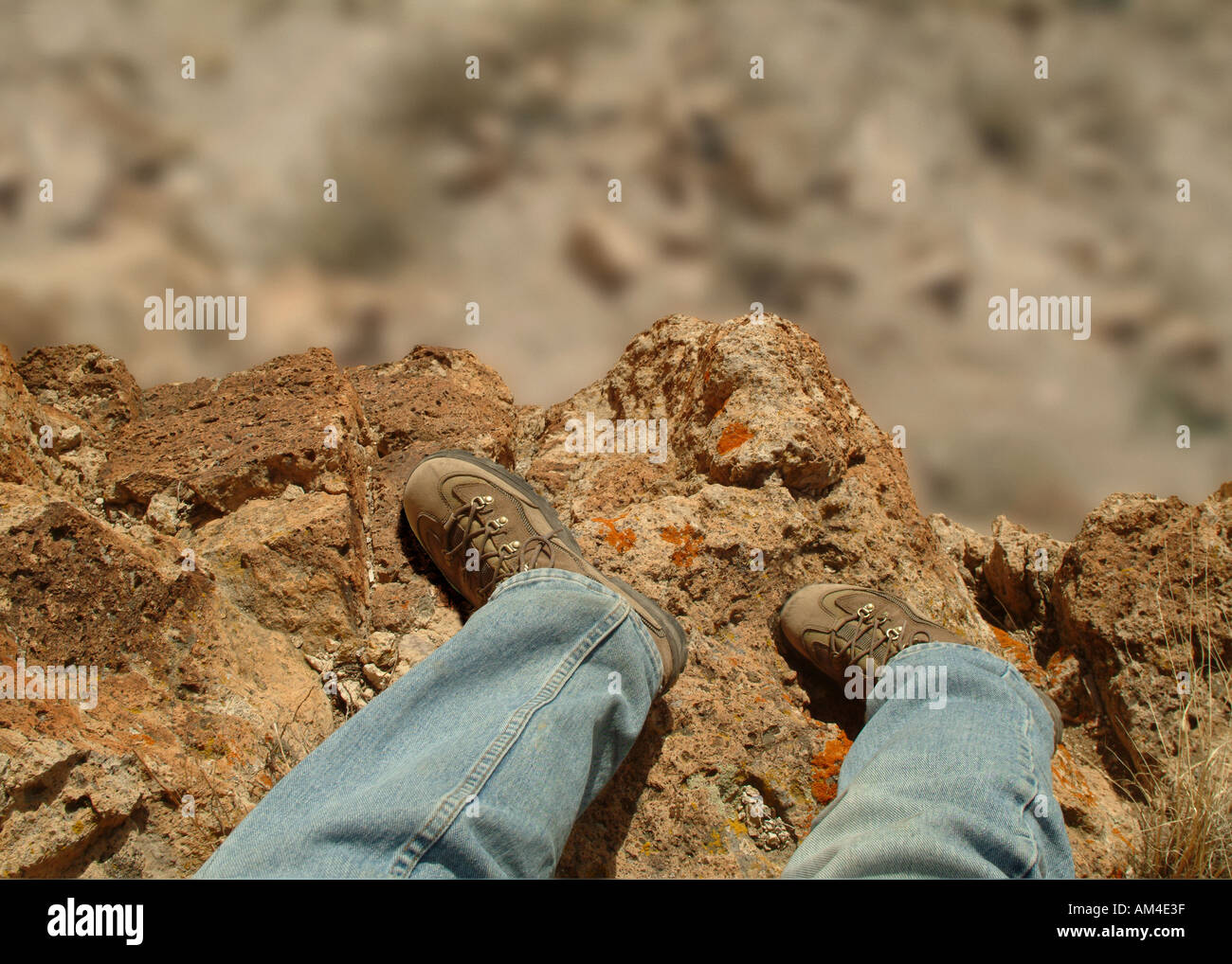 looking down over a cliff edge while a climber inches along a narrow ...