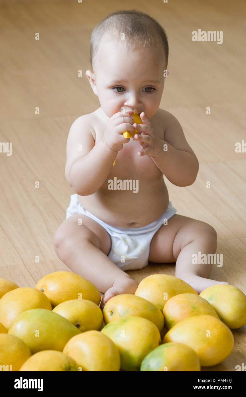 High angle view of a baby boy eating mango Stock Photo - Alamy