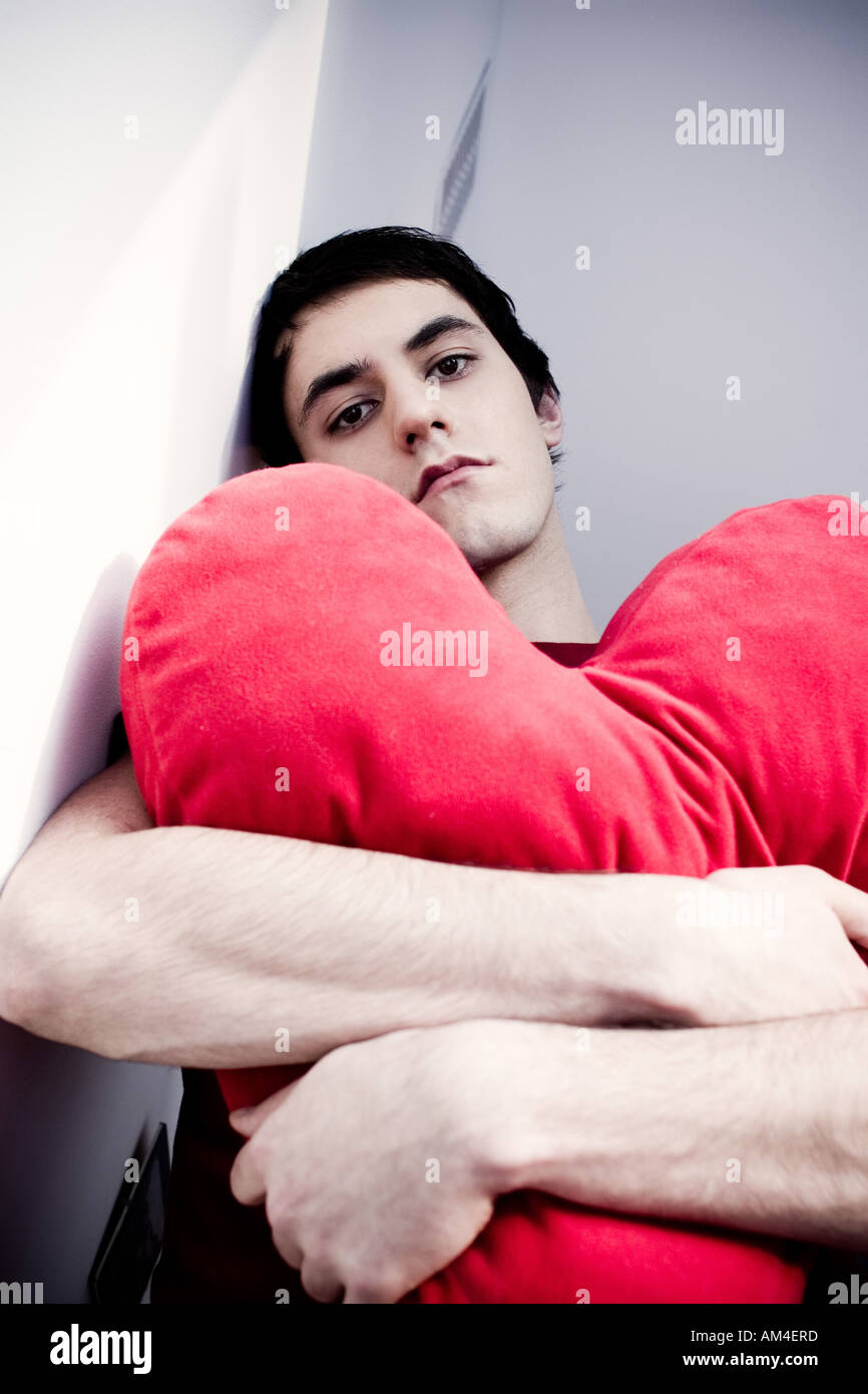 sad man hugging heart - shaped pillow Stock Photo - Alamy