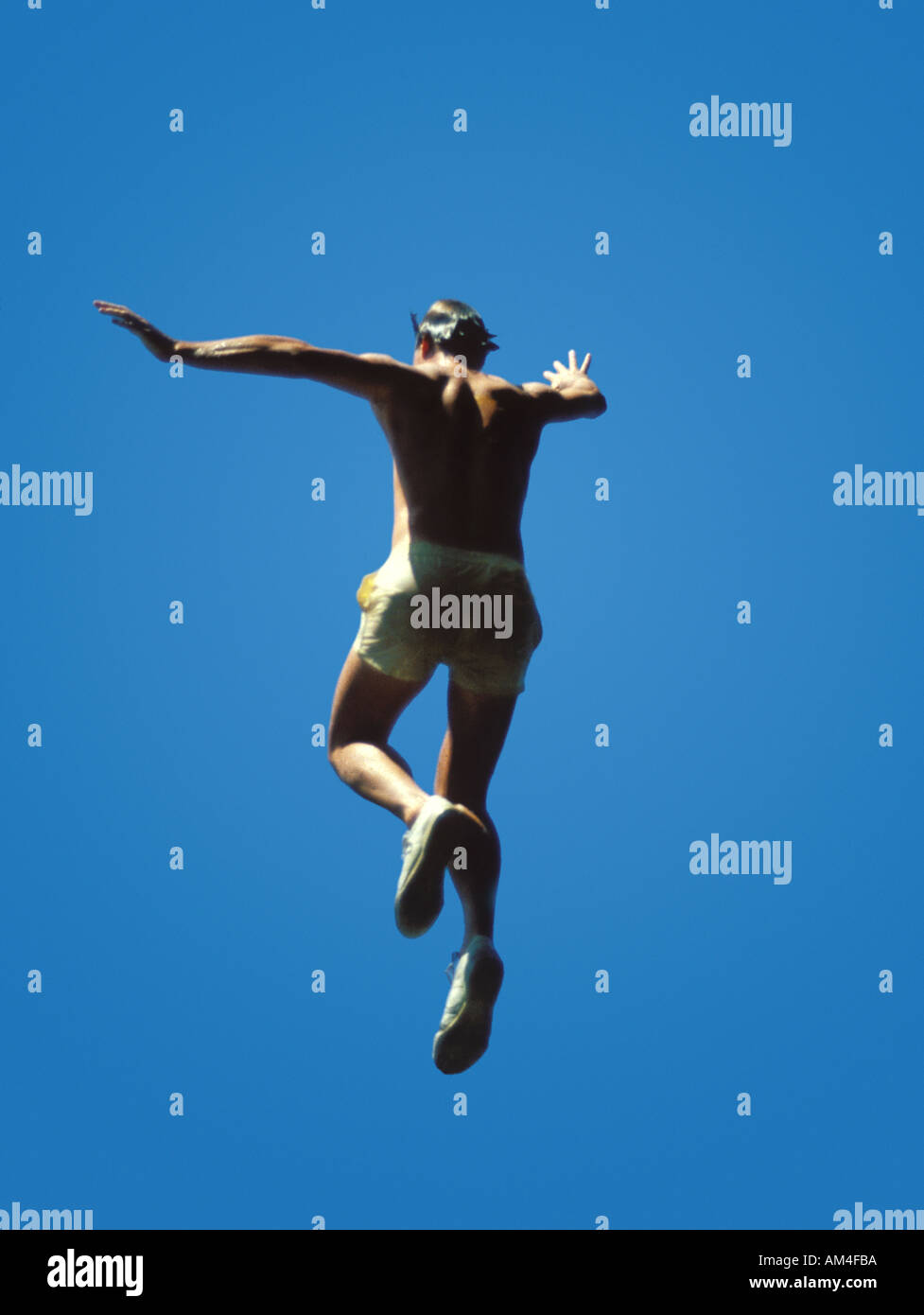 man jumps through the air. Here he has just let go of a rope swing over ...