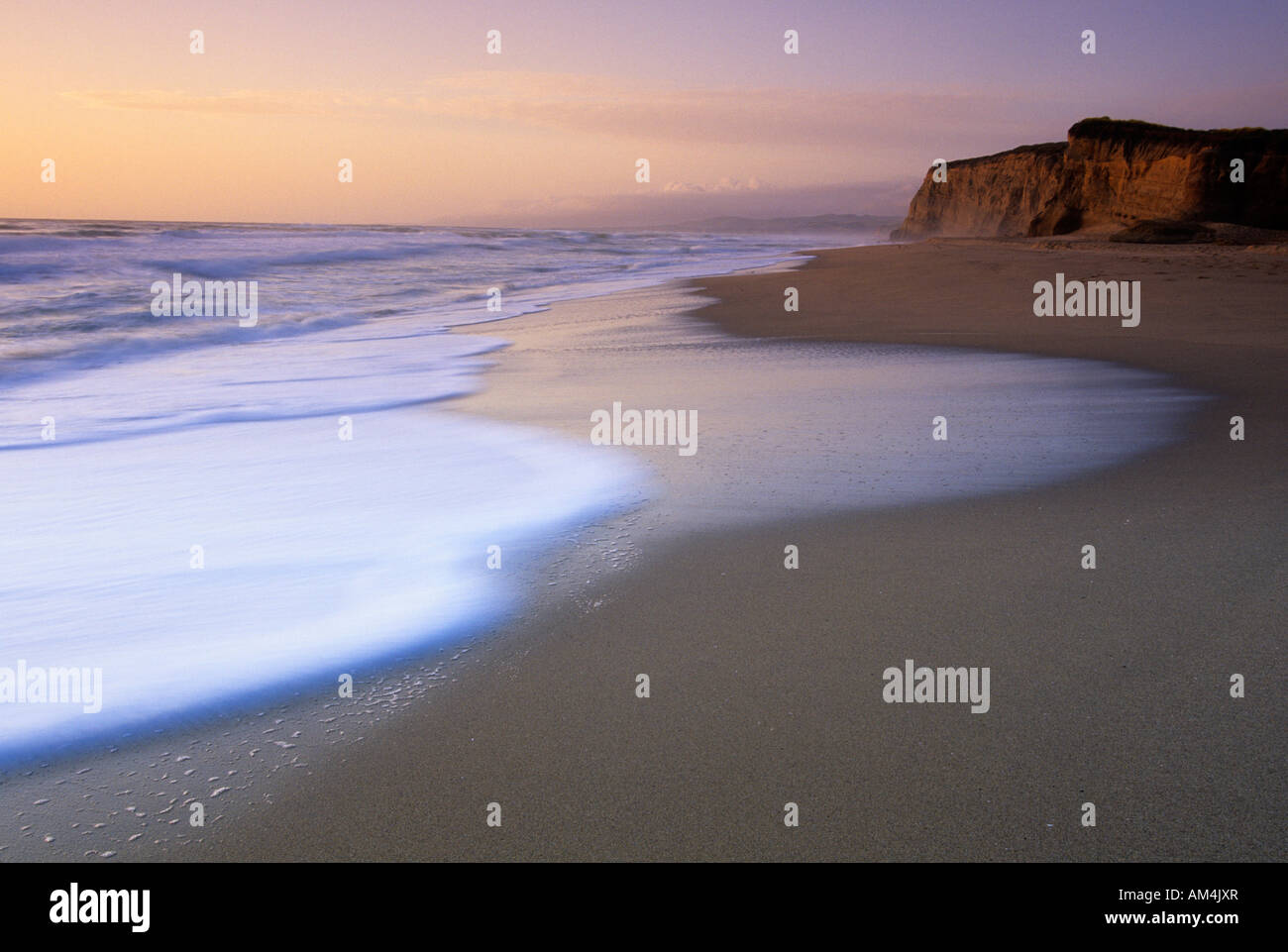 Waves wash up on the beach at sunset in Pomponio State Beach ...