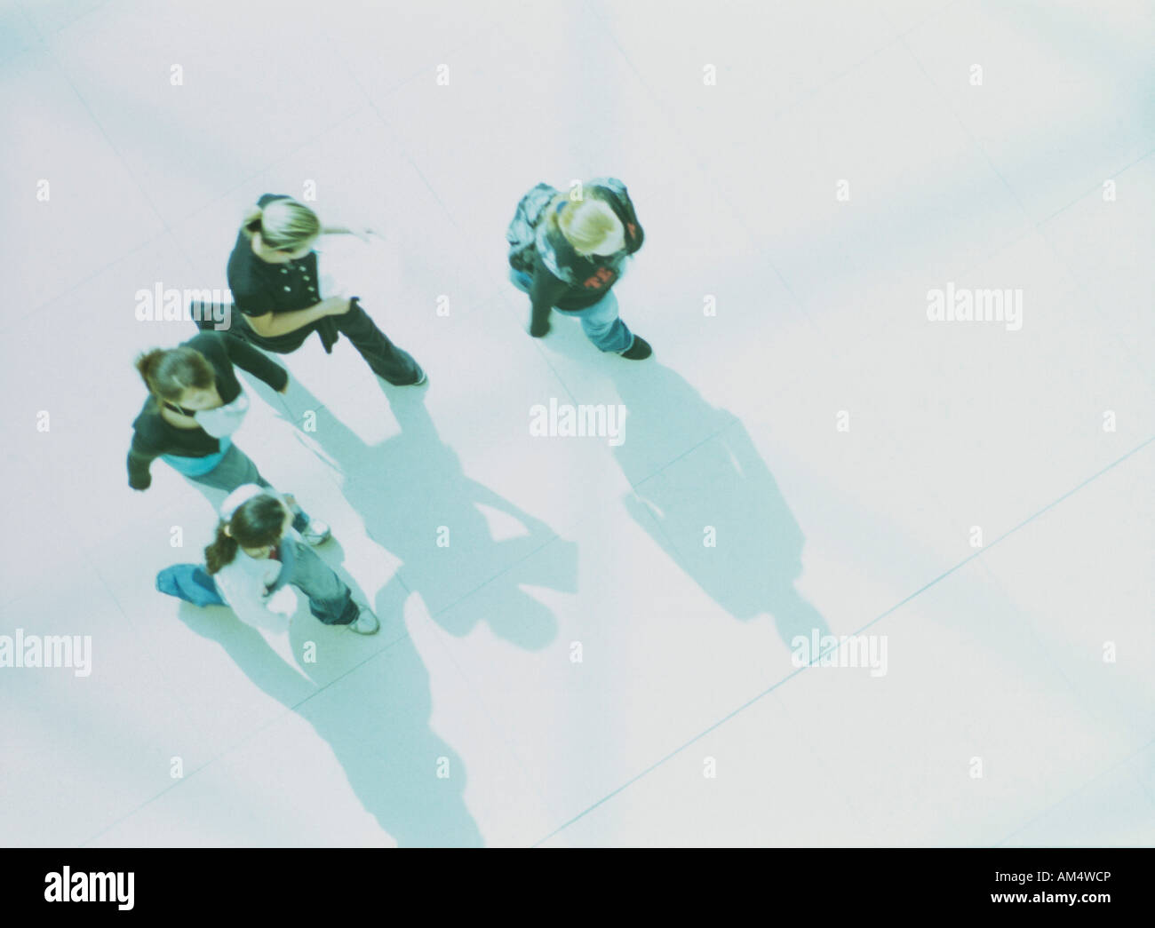 Four young people seen from above walking across across the floor of ...