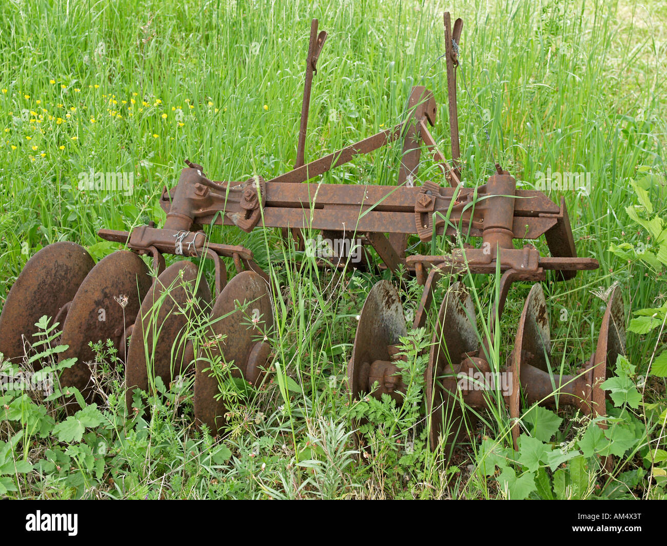 old broken rusty agricultural machine in green grass on meadow Stock ...