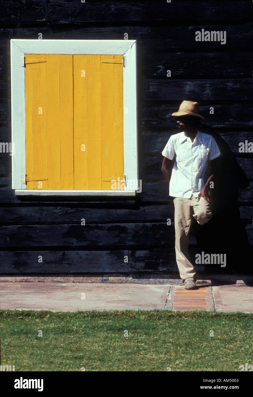 Antiguan native stands by a colorful old home Stock Photo - Alamy