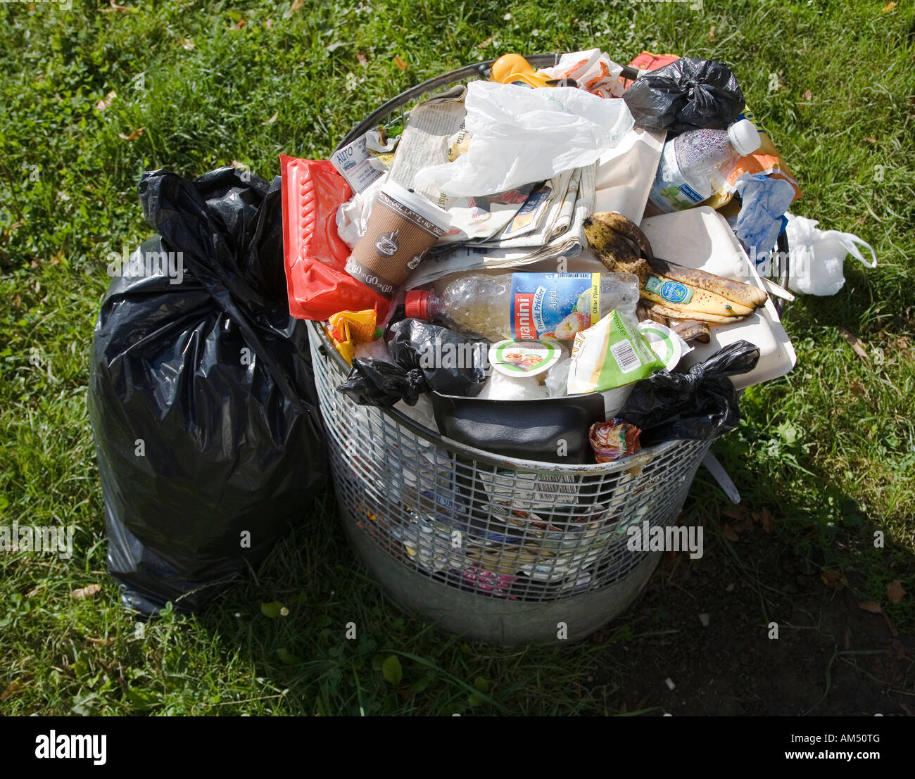 Overflowing rubbish basket and filled black bag awaiting collection on ...