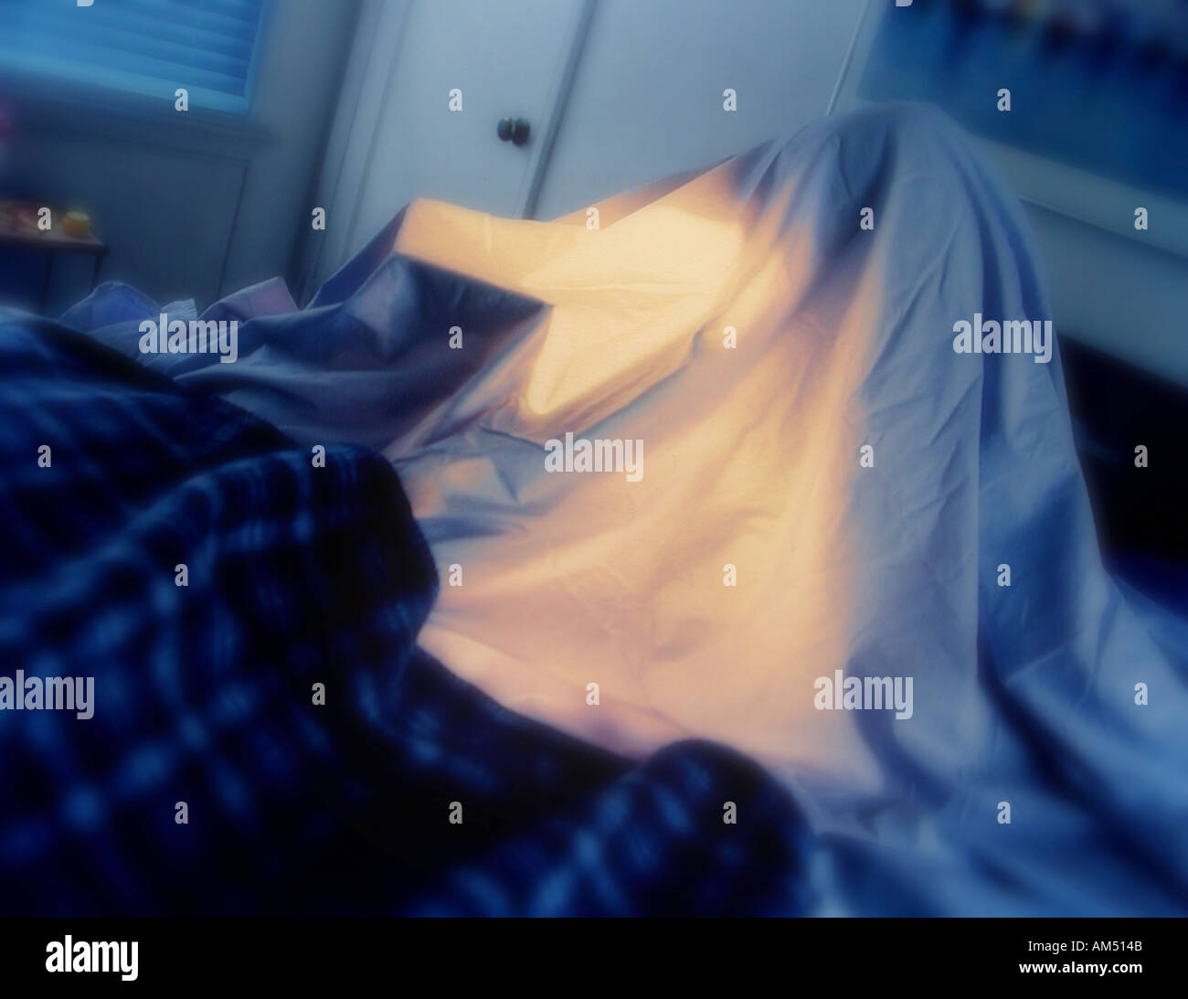 a child reading or playing under of the sheets with a flashlight Stock ...