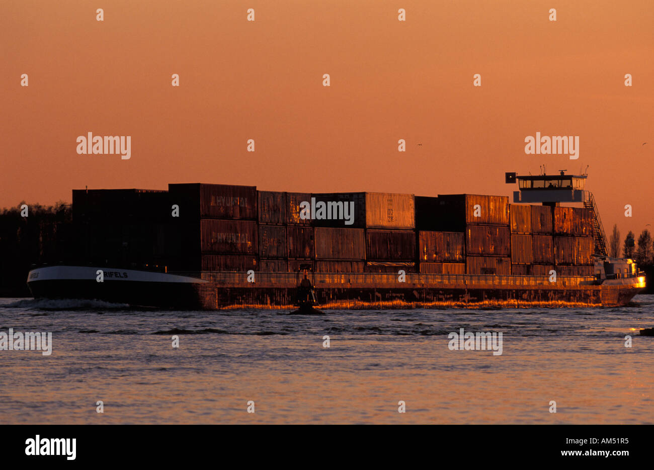 A container ship sailing upstream the Waal river at dusk Stock Photo ...